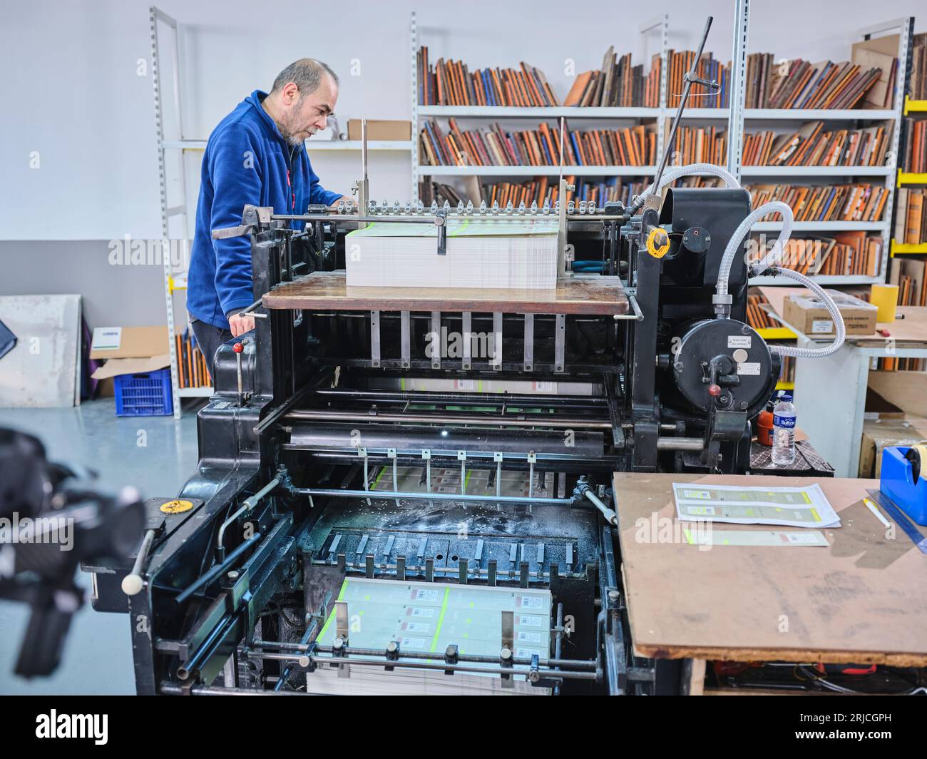 people working in a sticker printing factory. worker uses a stickier ...