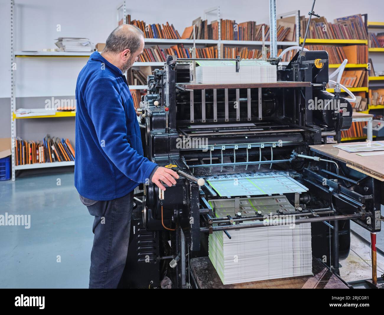 people working in a sticker printing factory. worker uses a stickier ...