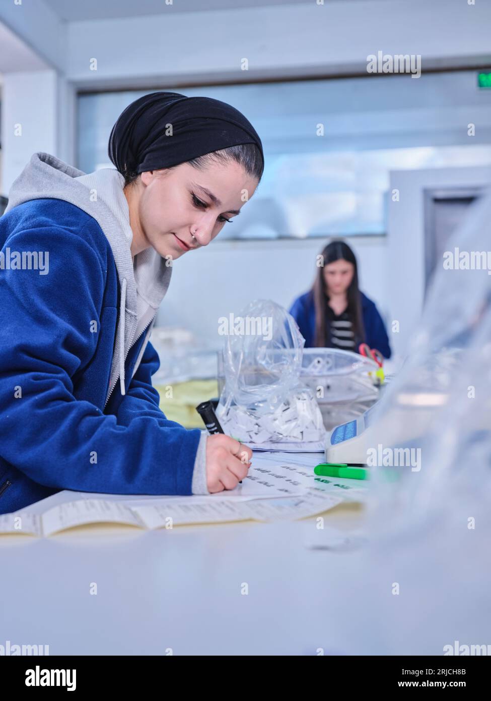 people working in a sticker printing factory. worker uses a stickier ...