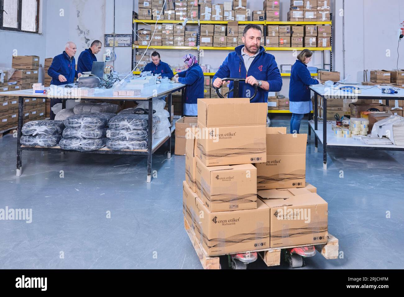 people working in a sticker printing factory. worker uses a stickier ...