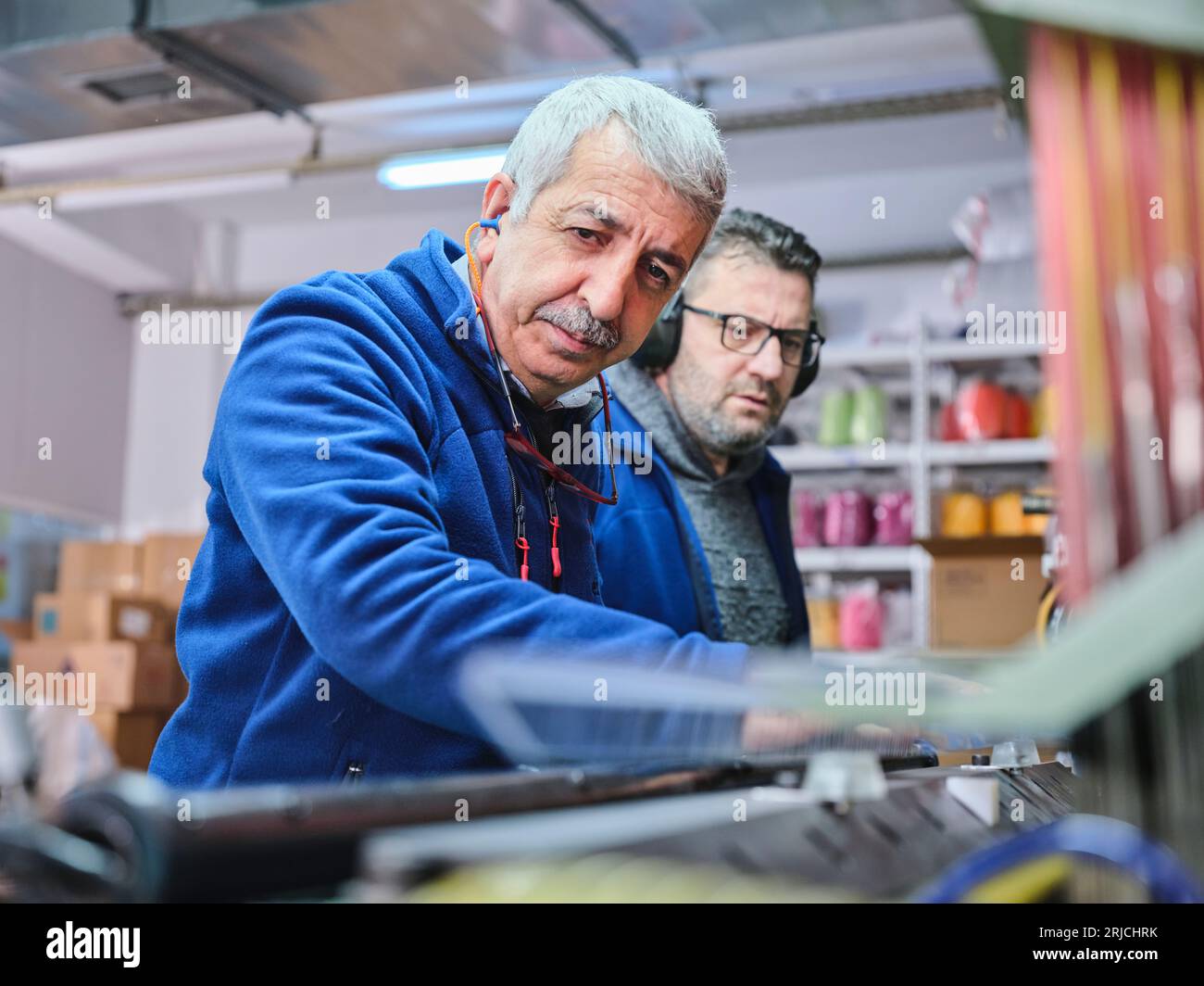 people working in a sticker printing factory. worker uses a stickier ...