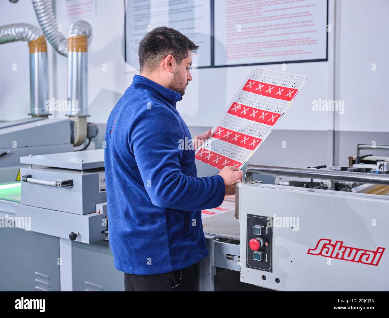 people working in a sticker printing factory. worker uses a stickier ...