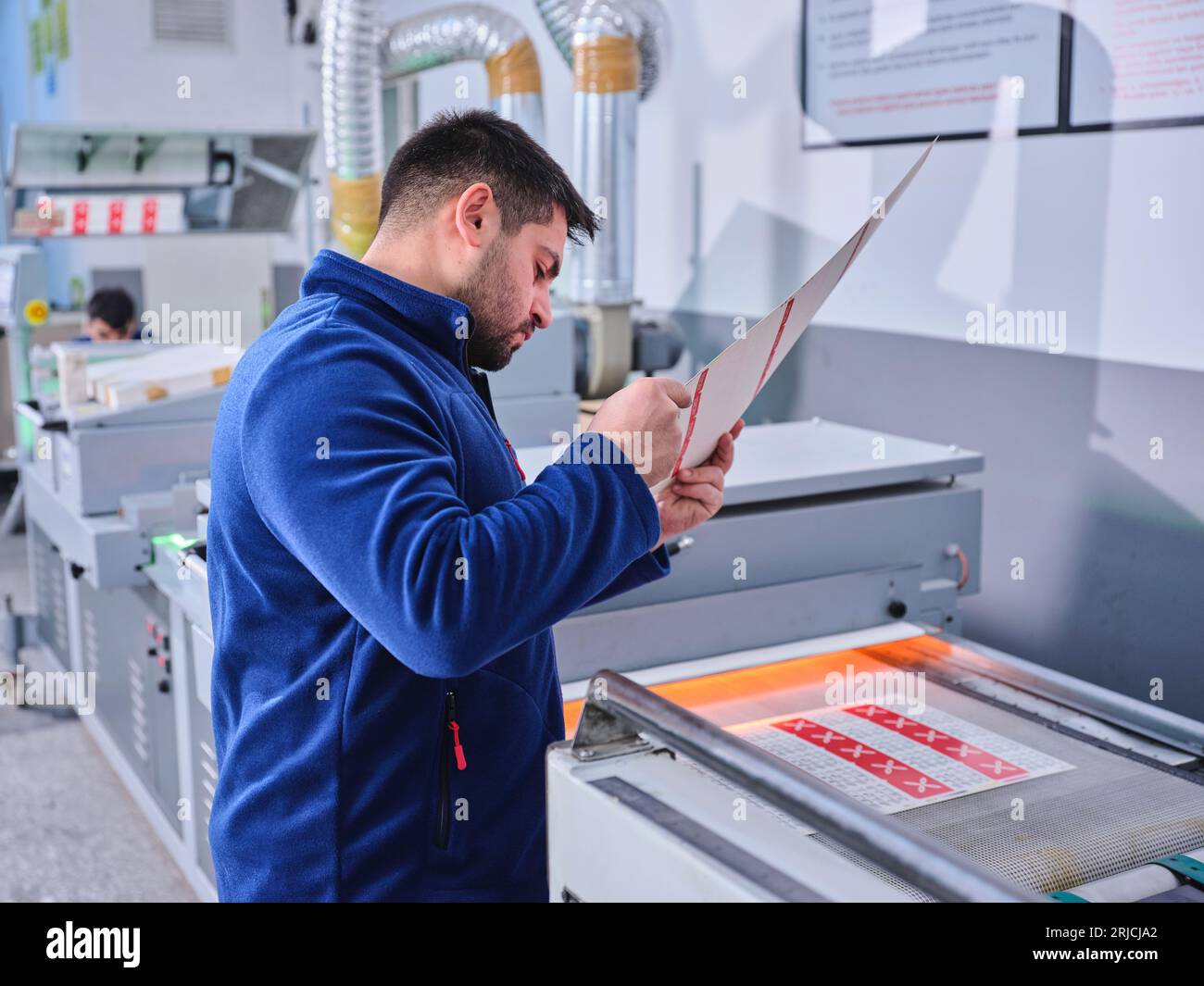 people working in a sticker printing factory. worker uses a stickier ...