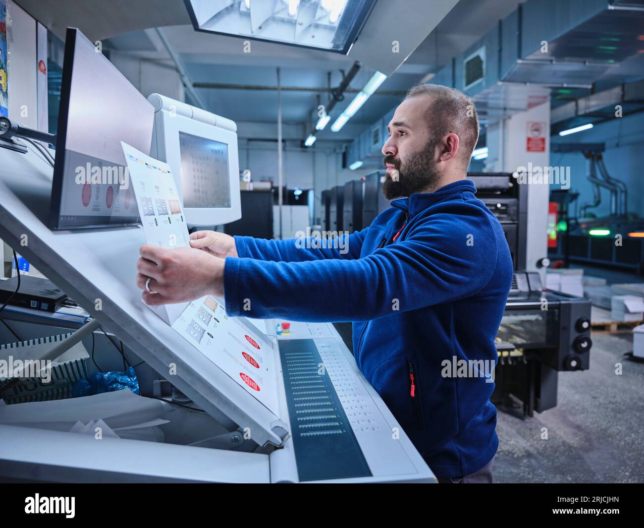people working in a sticker printing factory. worker uses a stickier ...
