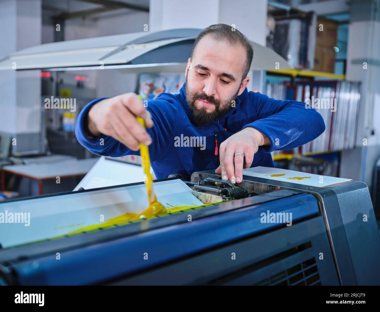 people working in a sticker printing factory. worker uses a stickier ...