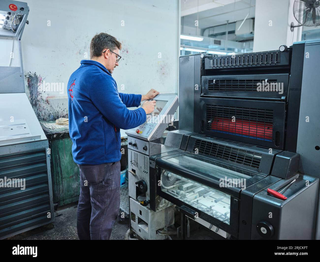 people working in a sticker printing factory. worker uses a stickier ...