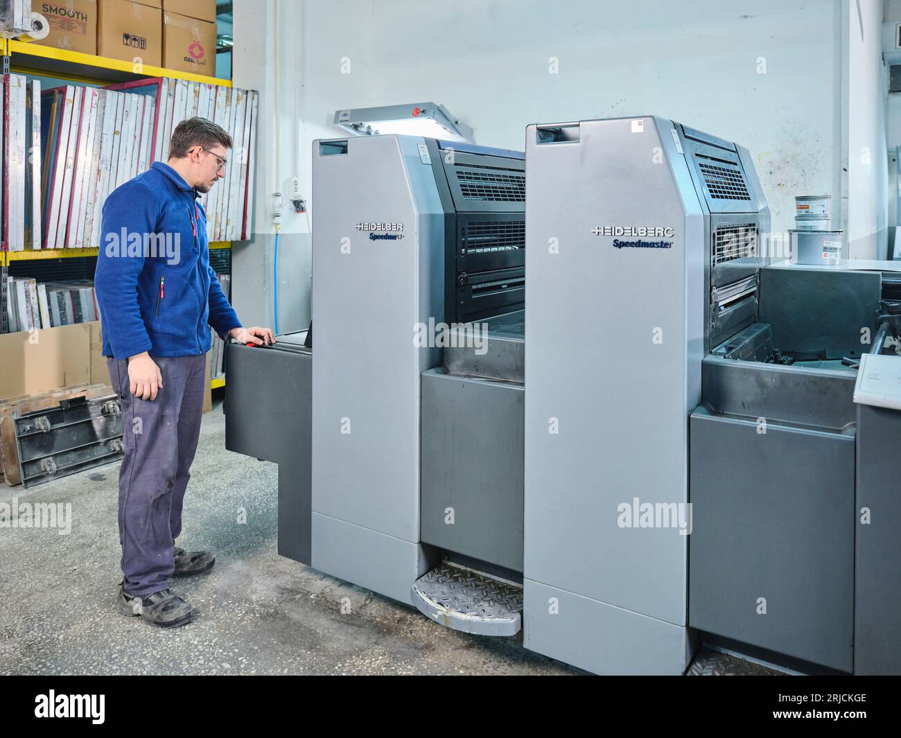 people working in a sticker printing factory. worker uses a stickier ...