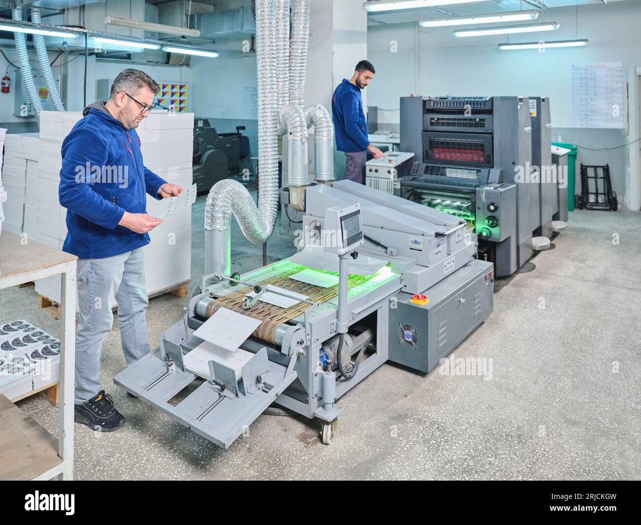 people working in a sticker printing factory. worker uses a stickier ...