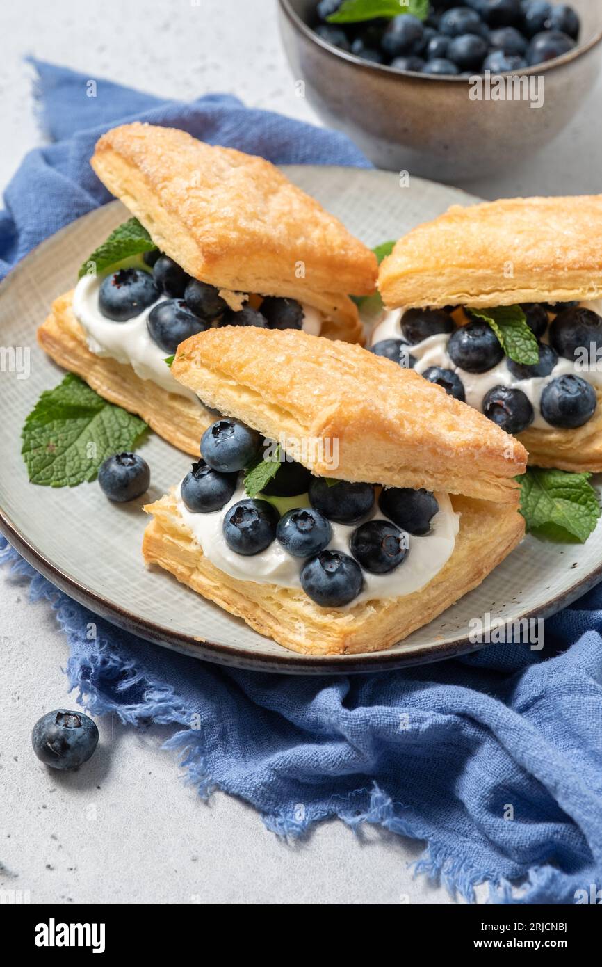 Stuffed homemade puff cookies with whipped cream and blueberries Stock ...
