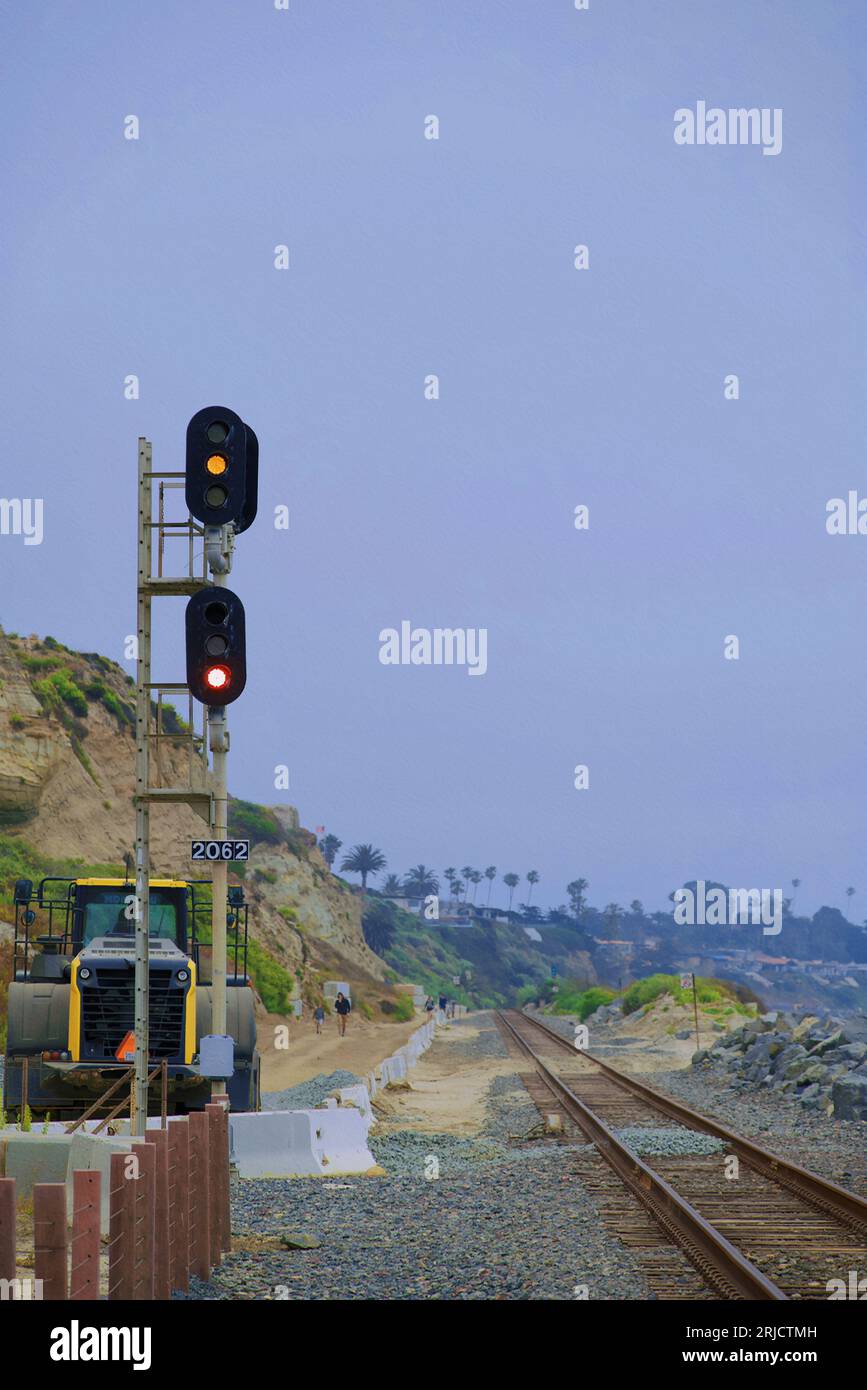 A bright yellow bulldozer parked on a gravel road beside a railroad ...