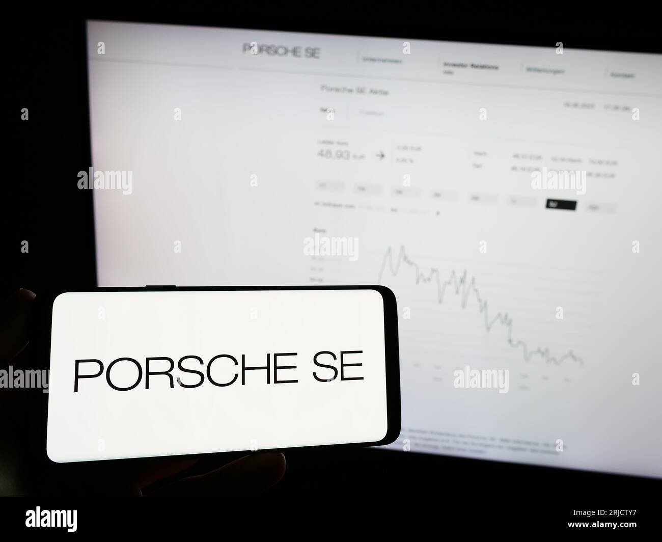 Person holding mobile phone with logo of German company Porsche ...