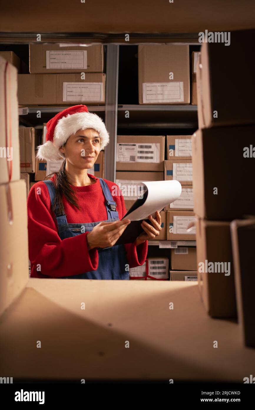 Female inventory manager checks stock, writing in clipboard working at ...