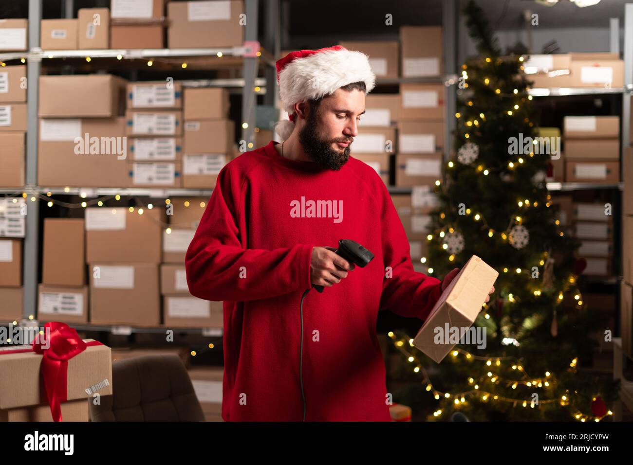 Warehouse worker wearing Santa hat scanning box in a large warehouse ...
