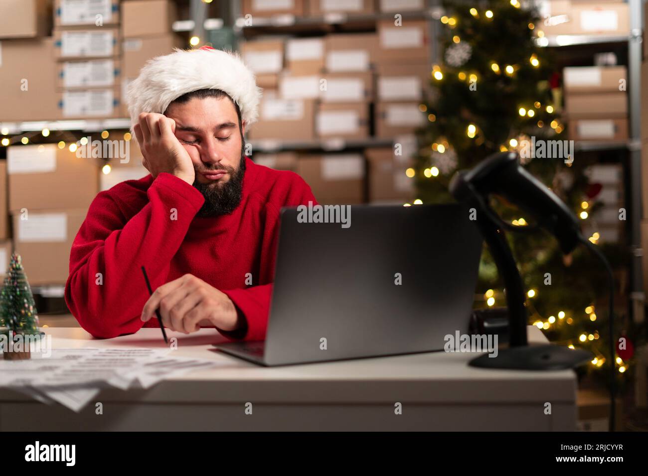 Retail warehouse employee sleeping while working at laptop computer ...
