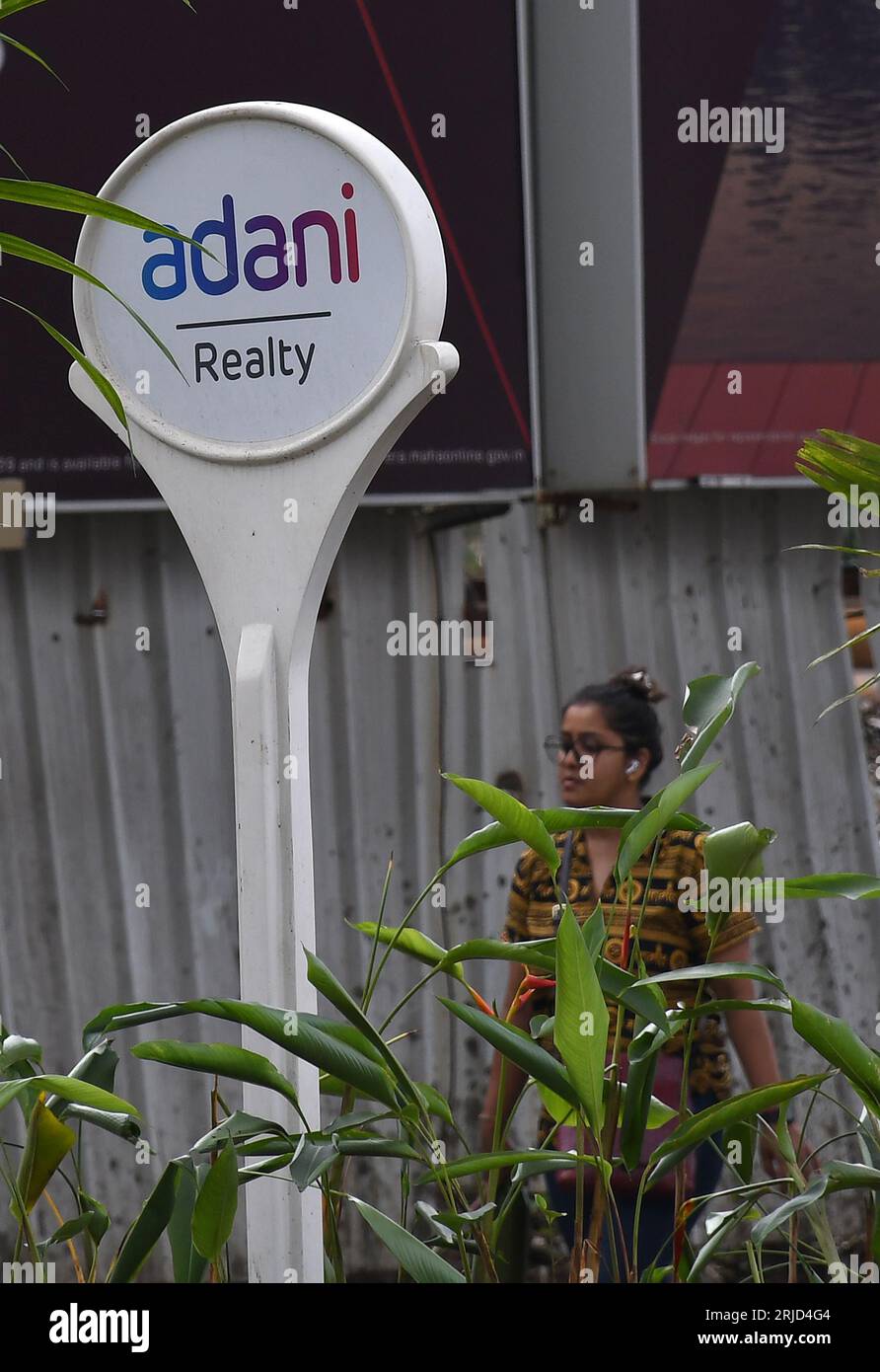 A woman walks on the road near Adani Realty logo in Mumbai. Adani ...