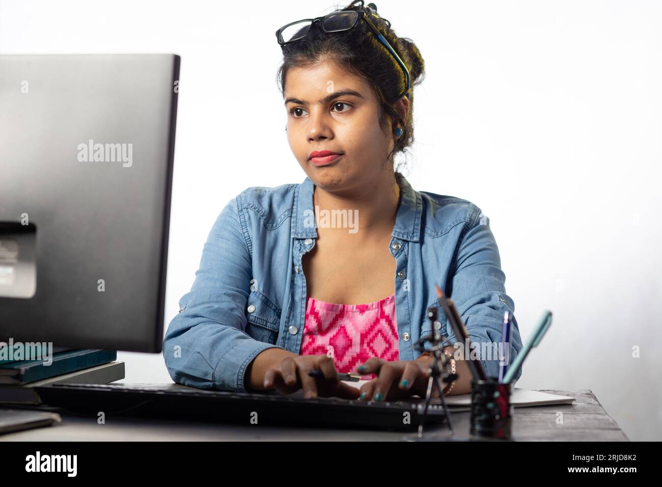 A pretty young Indian college student in eyeglasses studying with ...
