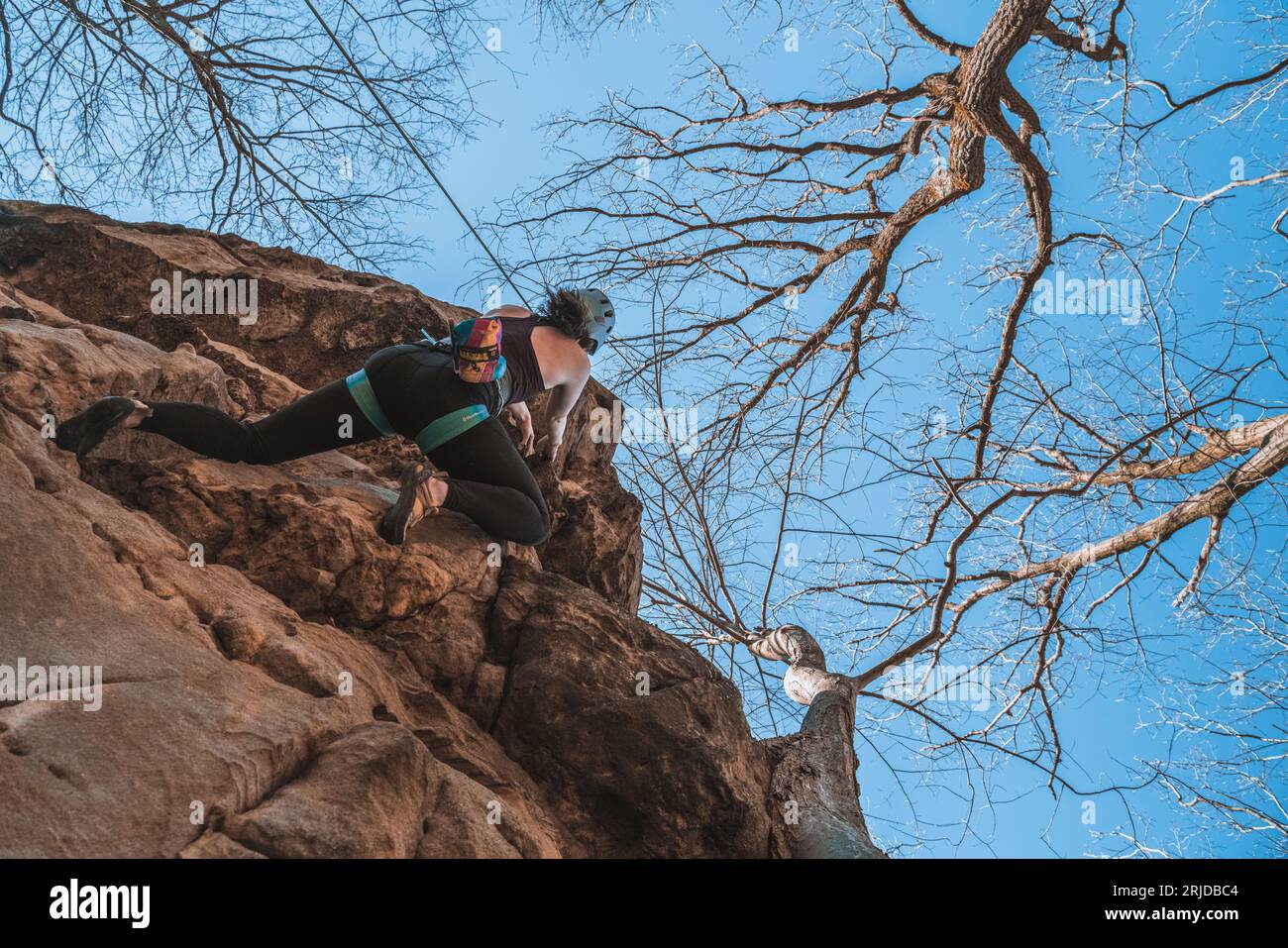 A female rock climber performing a top-rope climb in a natural setting ...