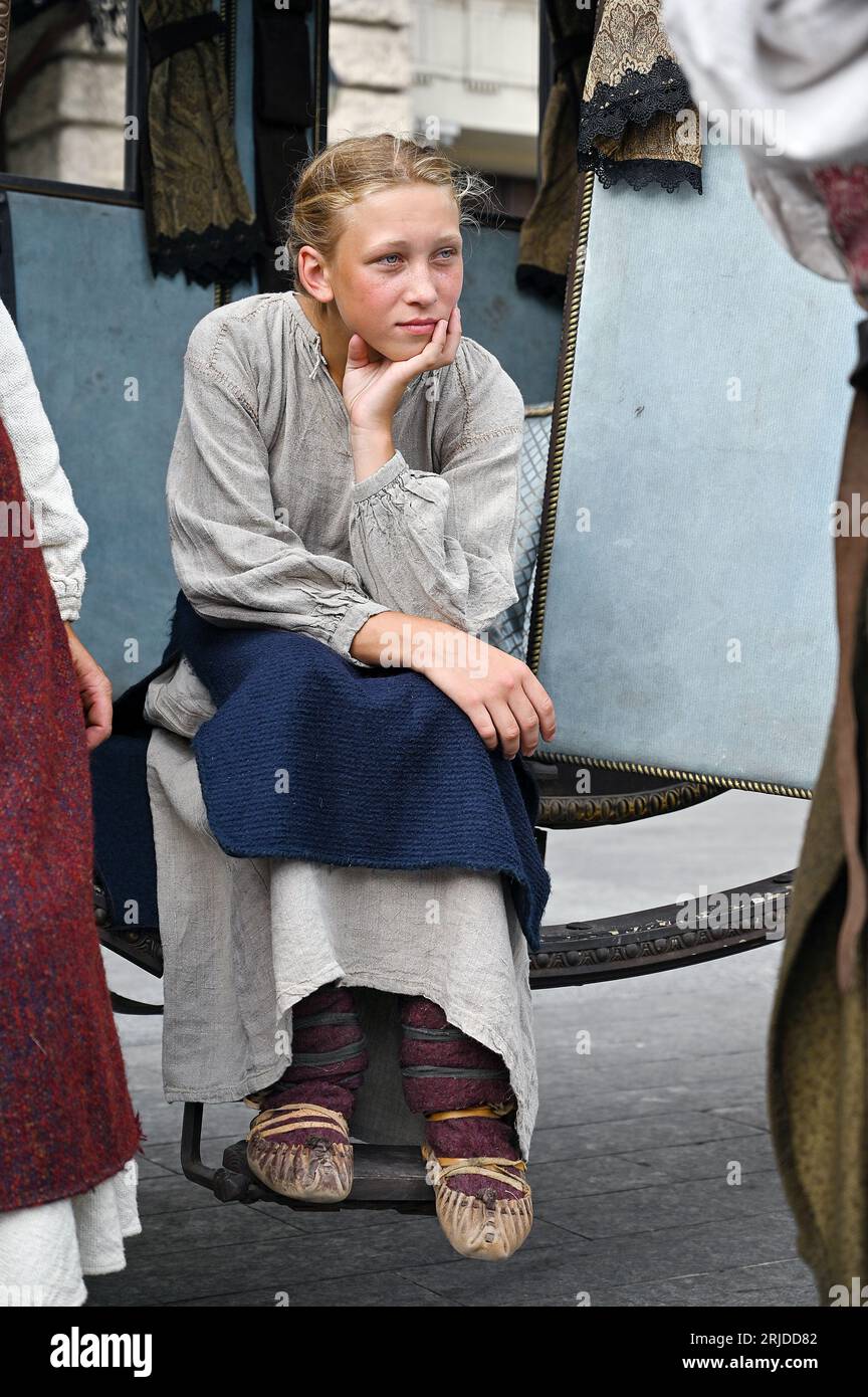 LVIV, UKRAINE - AUGUST 21, 2023 - An actress in a period costume sits ...