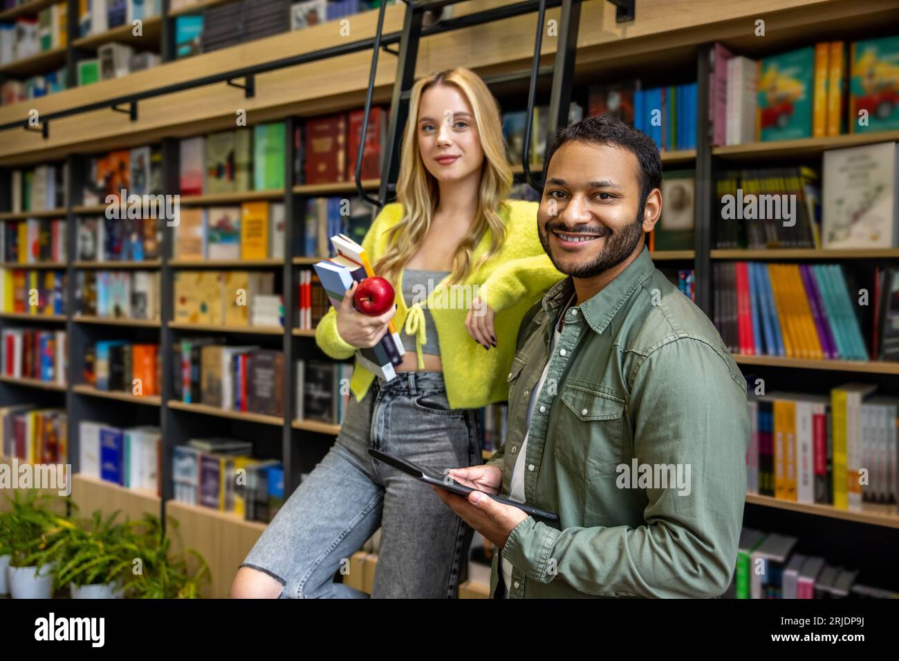Cute woman and dark-skinned man standing in the library Stock Photo - Alamy