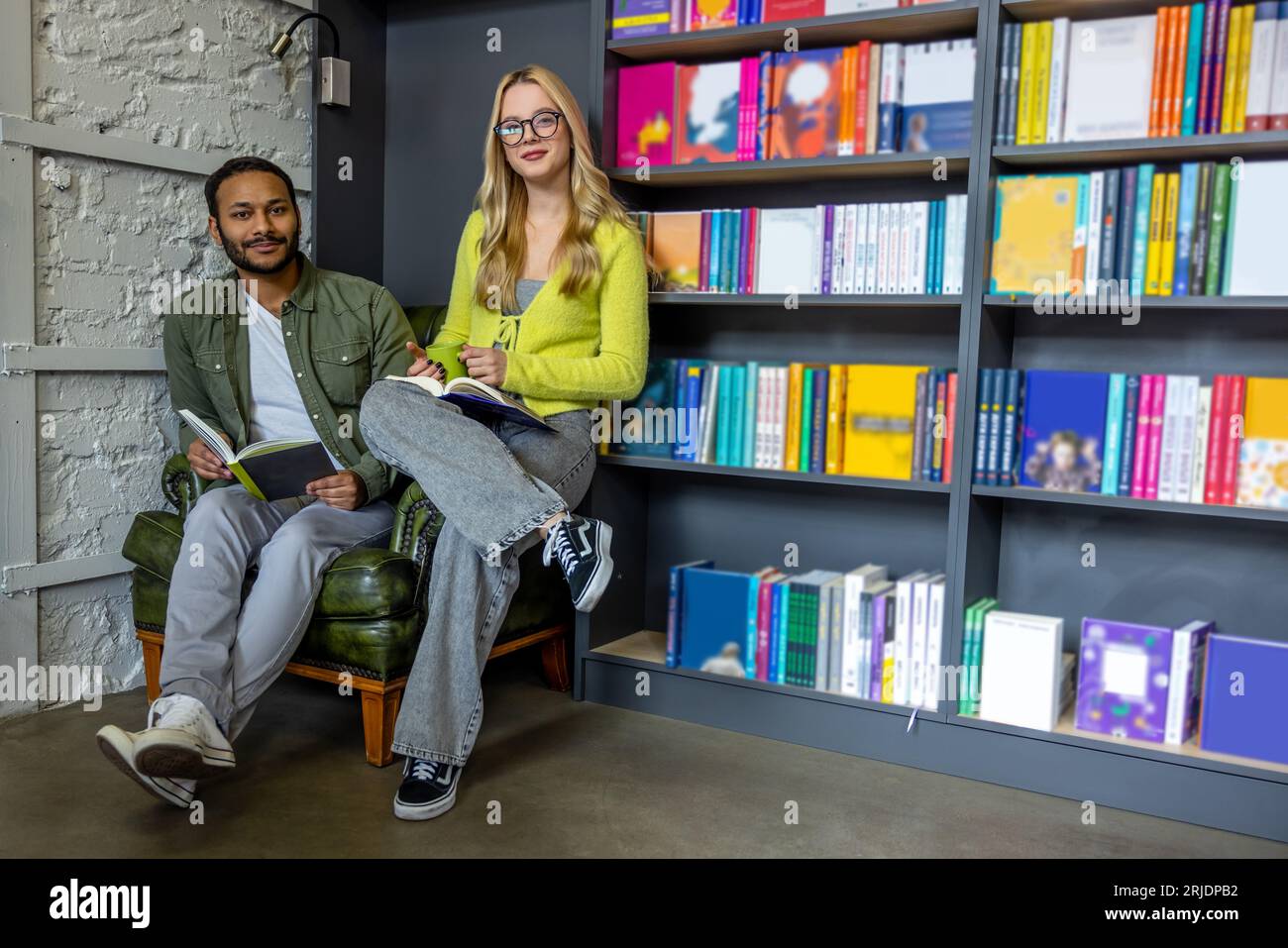 Pretty woman and young man sitting in the library Stock Photo - Alamy