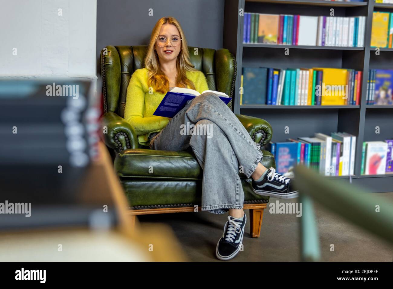 Cute blonde woman reading book in the library Stock Photo - Alamy