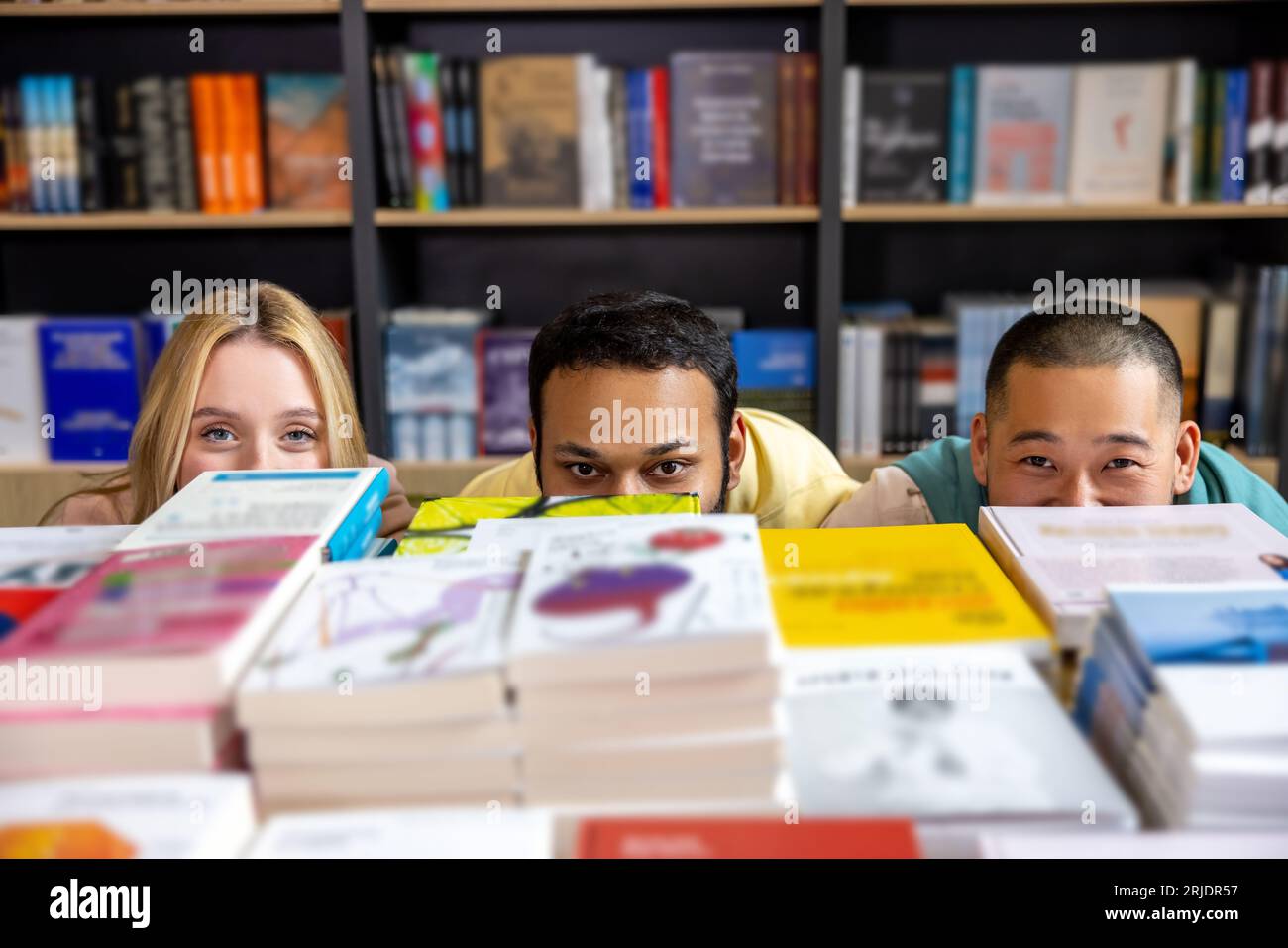Students hiding behind the bookshelves Stock Photo - Alamy