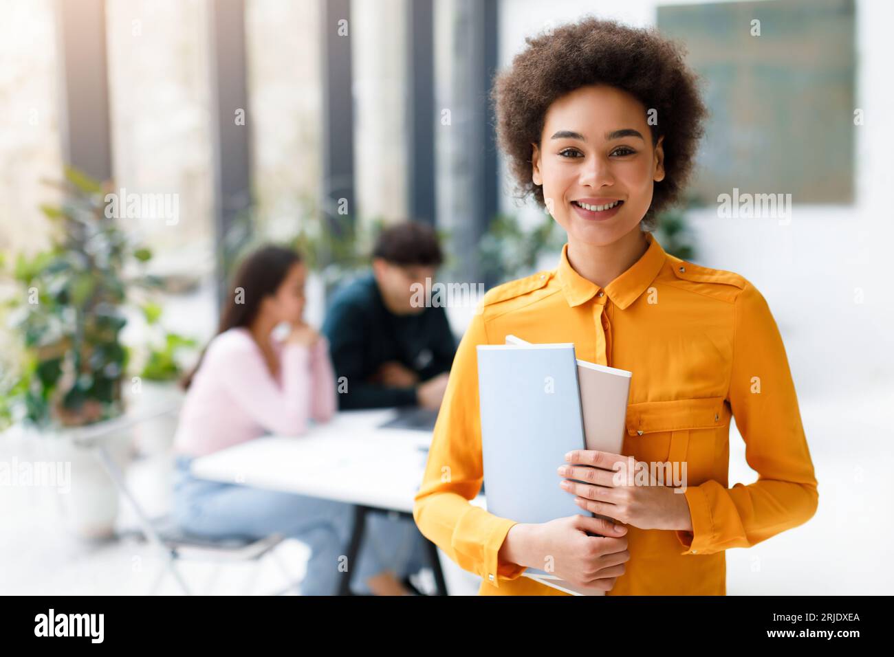 Portrait of happy black lady university student posing with notepads ...