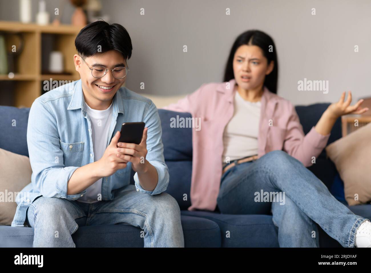 Asian Husband Texting On Smartphone Ignoring His Displeased Wife Indoor ...