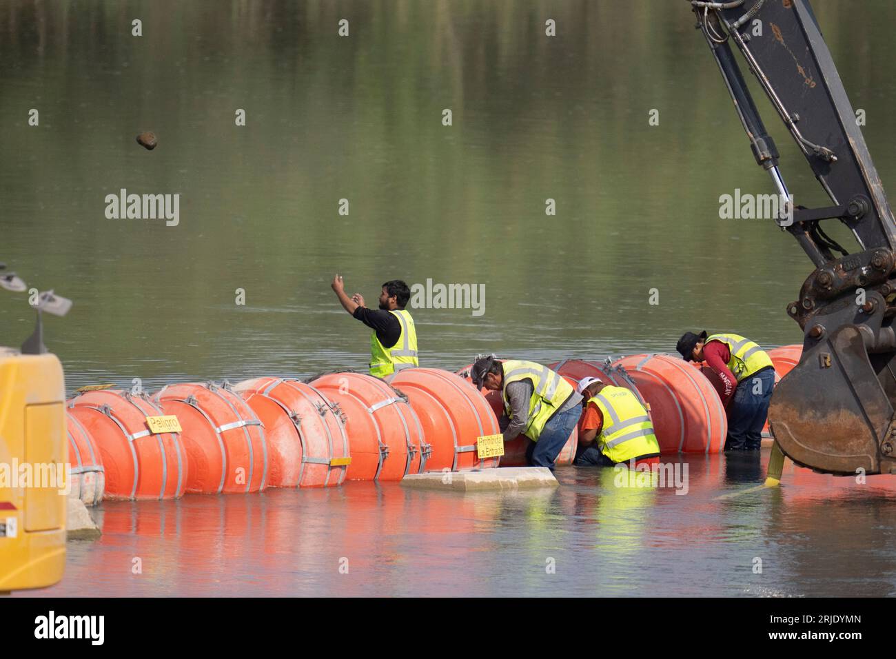 Workmen reposition a 1000-foot long string of buoys in a shallow spot ...