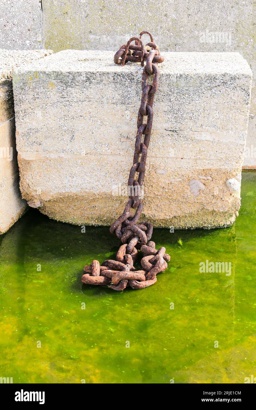 Concrete blocks on a puddle of water with reflections in the port of ...