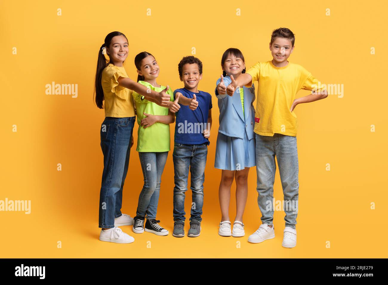 Happy multiracial children showing thumb ups and smiling, yellow ...