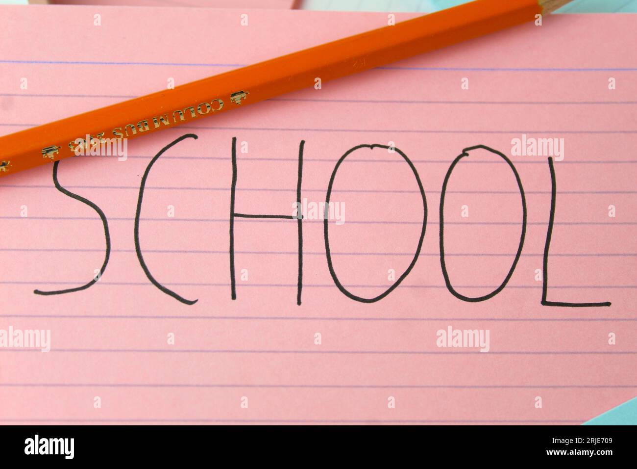 A photo of the word 'School' written on a pink flashcard with a pencil ...