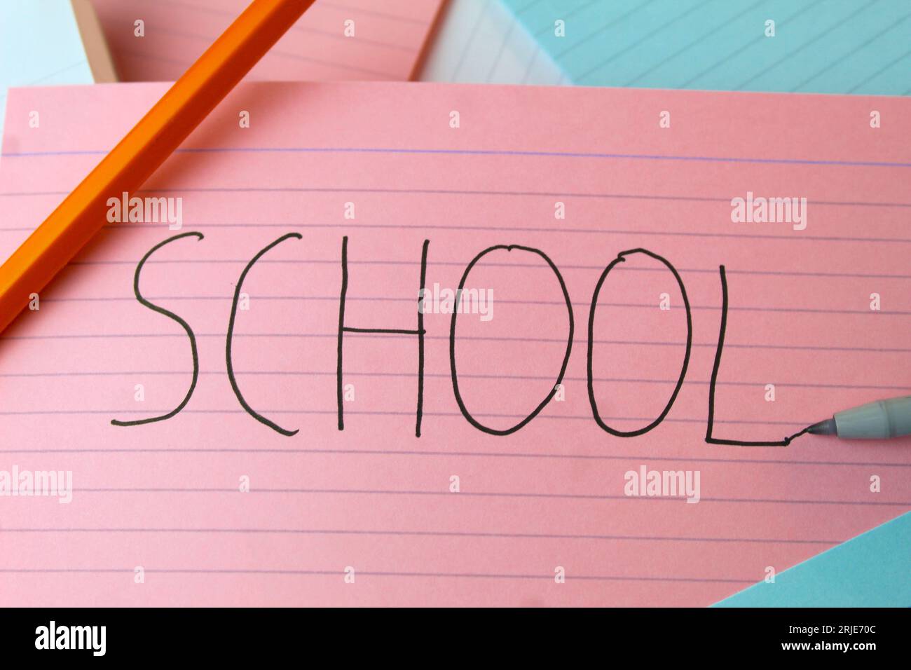 A photo of the word 'School' written on a pink flashcard with a pencil ...