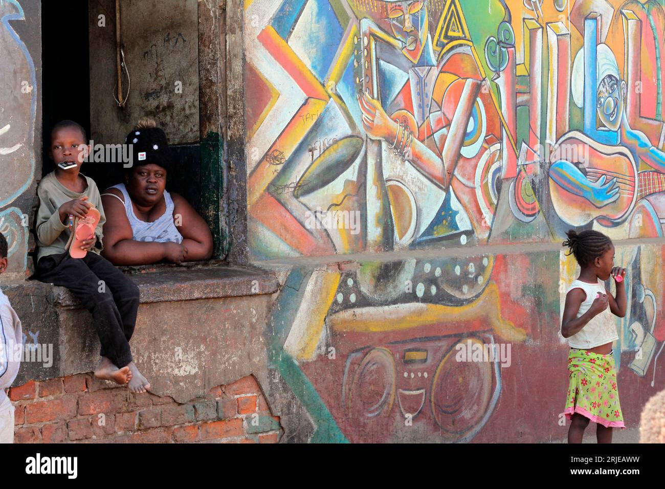 A woman and child look out of a hole in the wall at Matapi flats, while ...