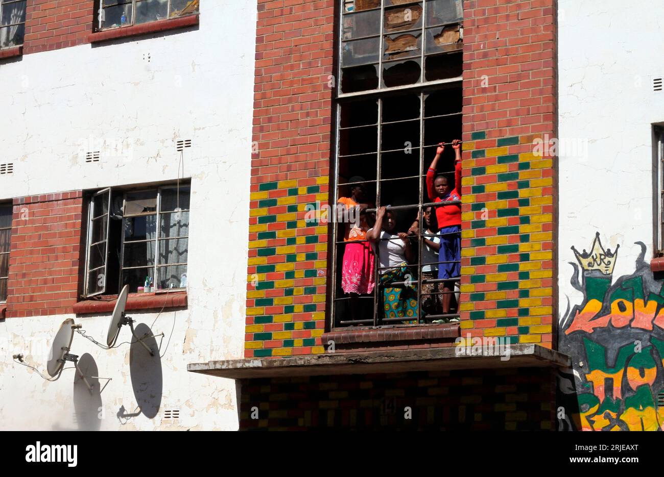 Some young people are looking through a broken window at Matapi flats ...
