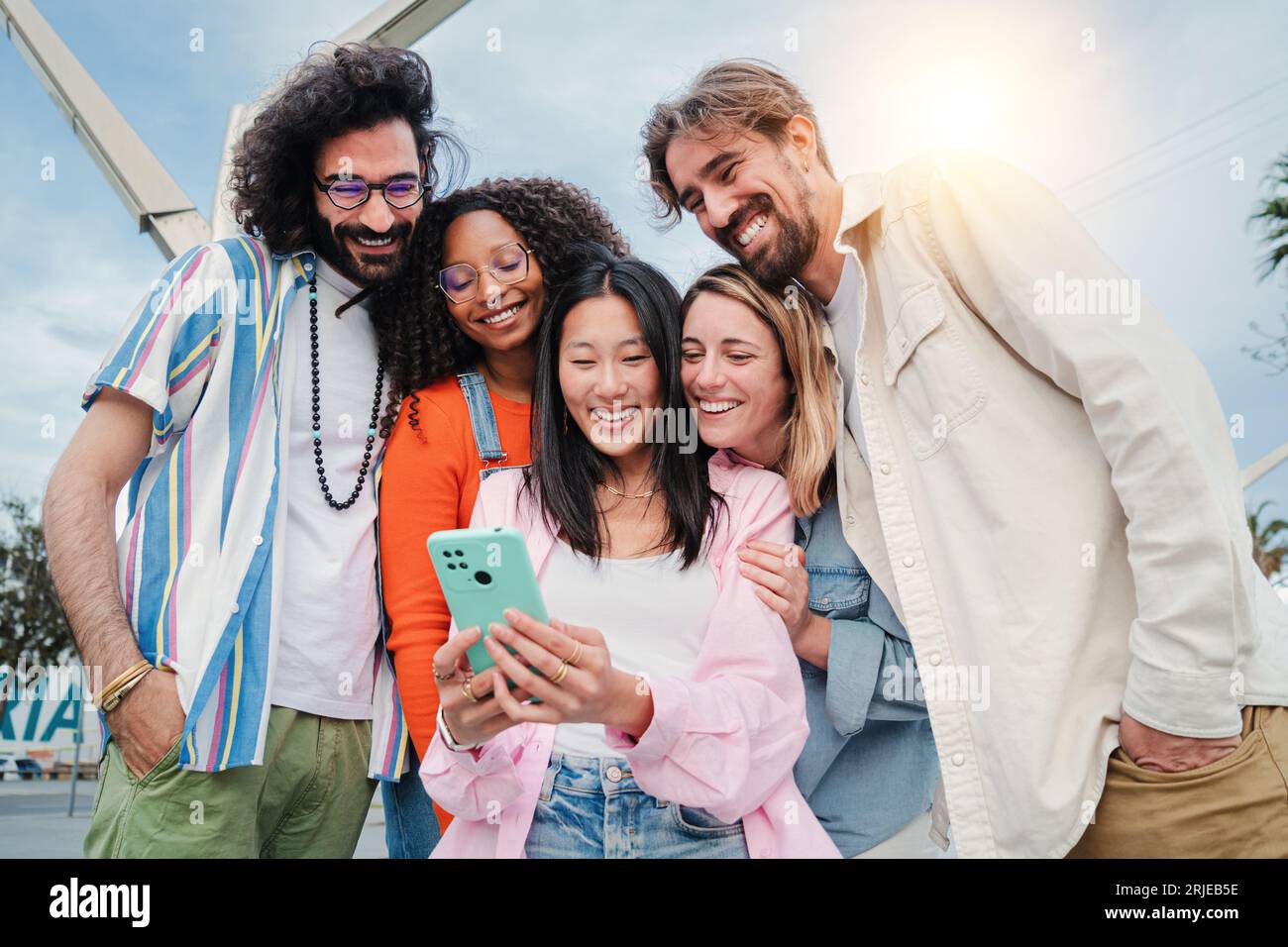 Multiracial group of young adult friends enjoying and smiling using a ...