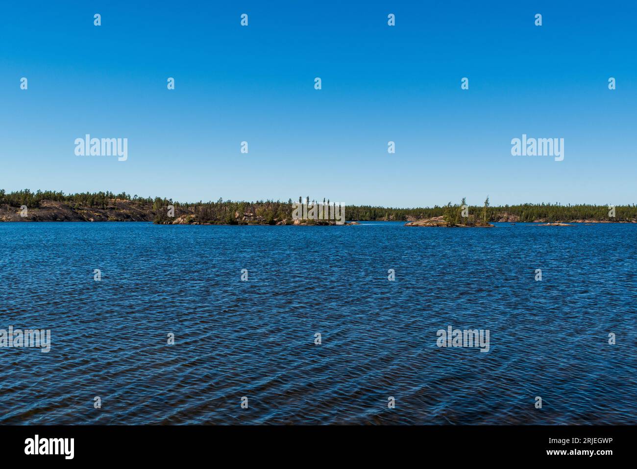 Beautiful blue lake ringed with forest sparkles in sunlight near ...