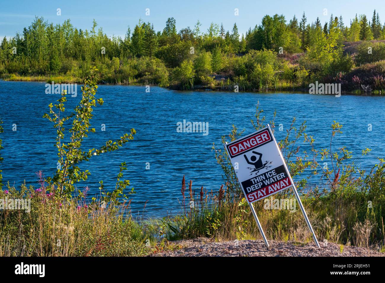 Beautiful blue lake, with thin ice warning, sparkles in sunlight near ...