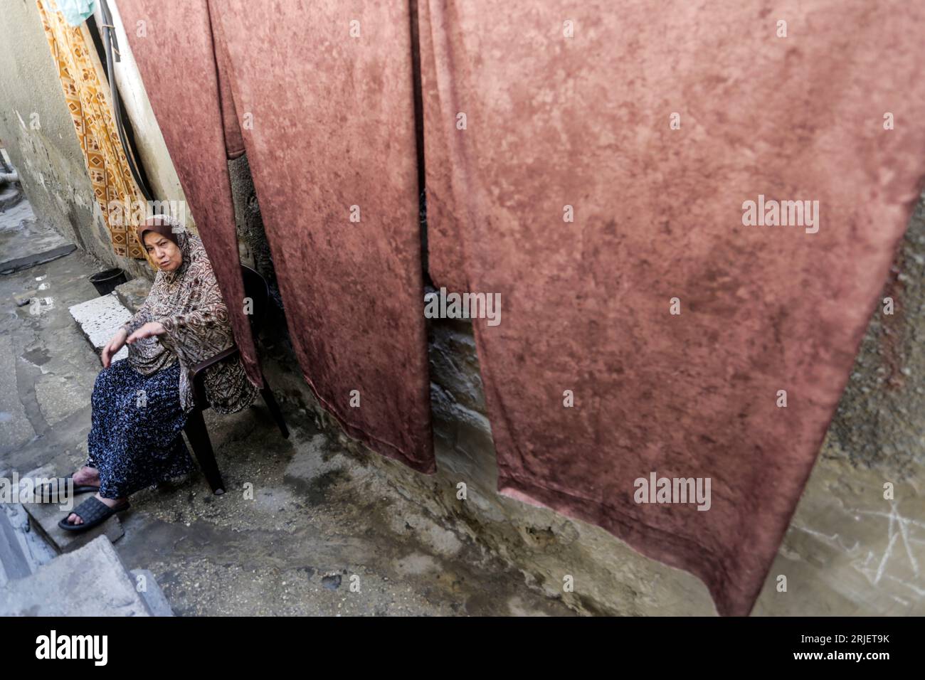 A Palestinian woman sits outside his house in Al-Shati refugee camp ...