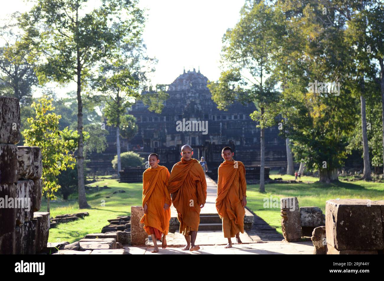 Monks walking against the backdrop of the sun and ancient Cambodian ...