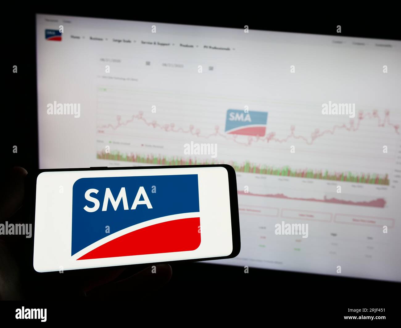 Person holding mobile phone with logo of German company SMA Solar ...