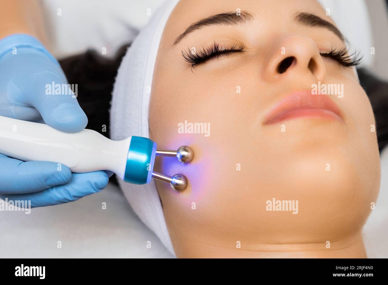 Application of microcurrent massage device on female face by ...