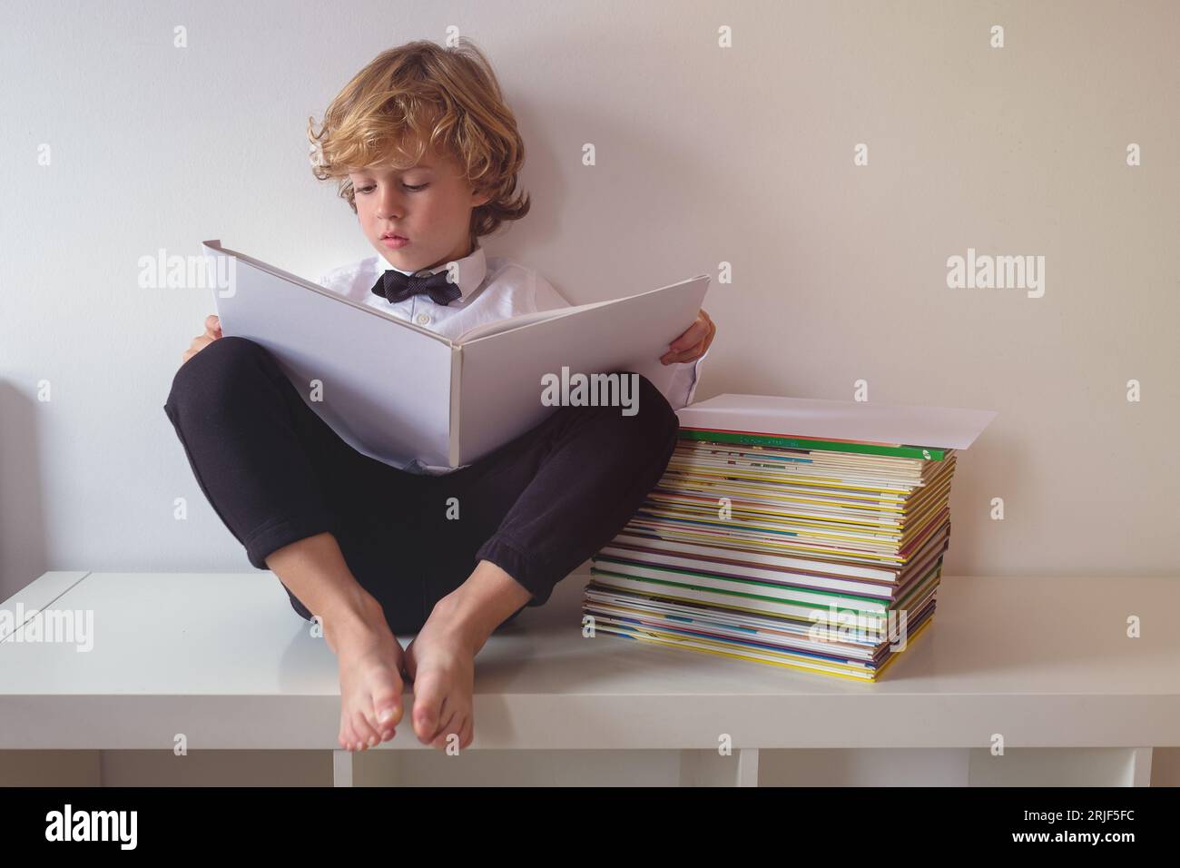 Full body of concentrated barefoot boy in formal wear with bow tie ...