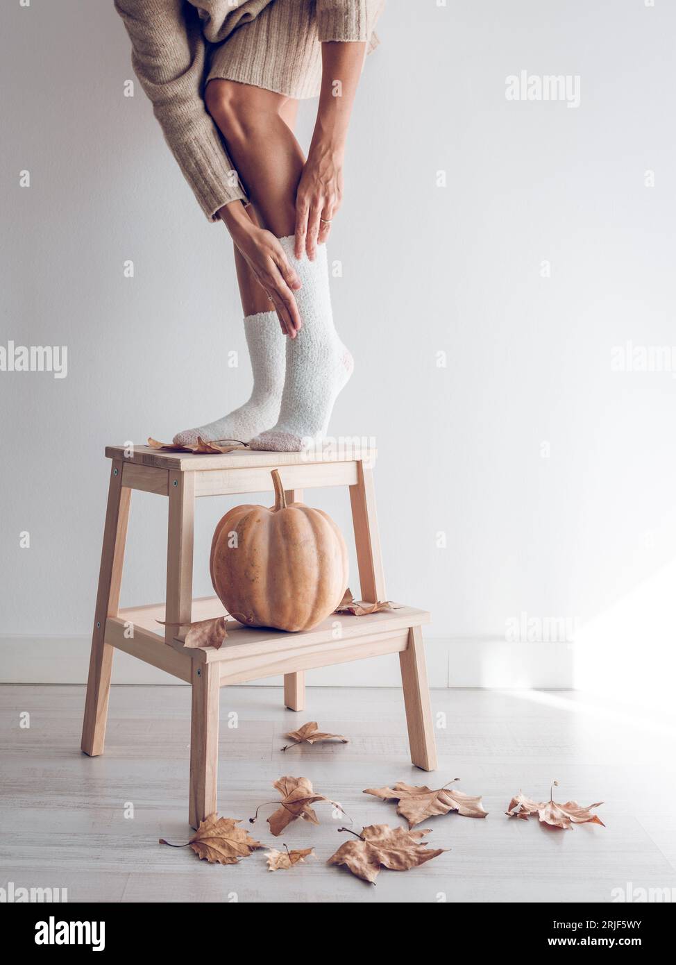 Crop unrecognizable woman wearing white socks standing on wooden stand ...