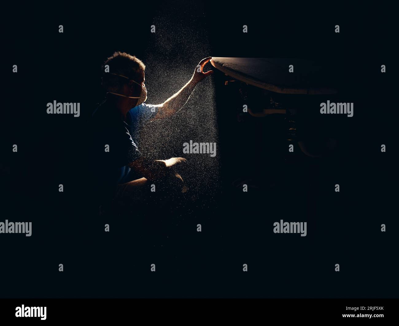 Side view of male master in respirator sitting on haunches in dark ...