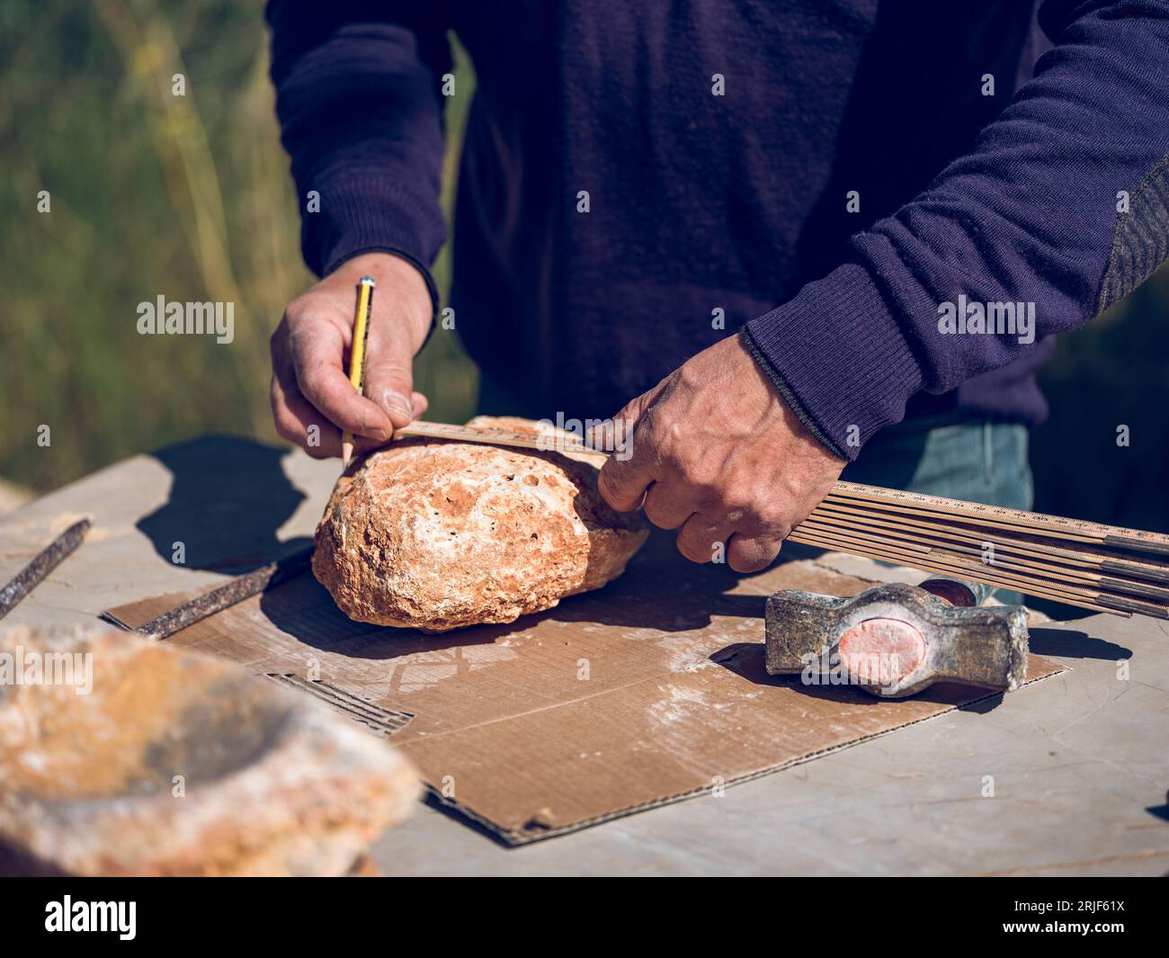 Crop anonymous elder male artisan measuring stone with ruler and making ...
