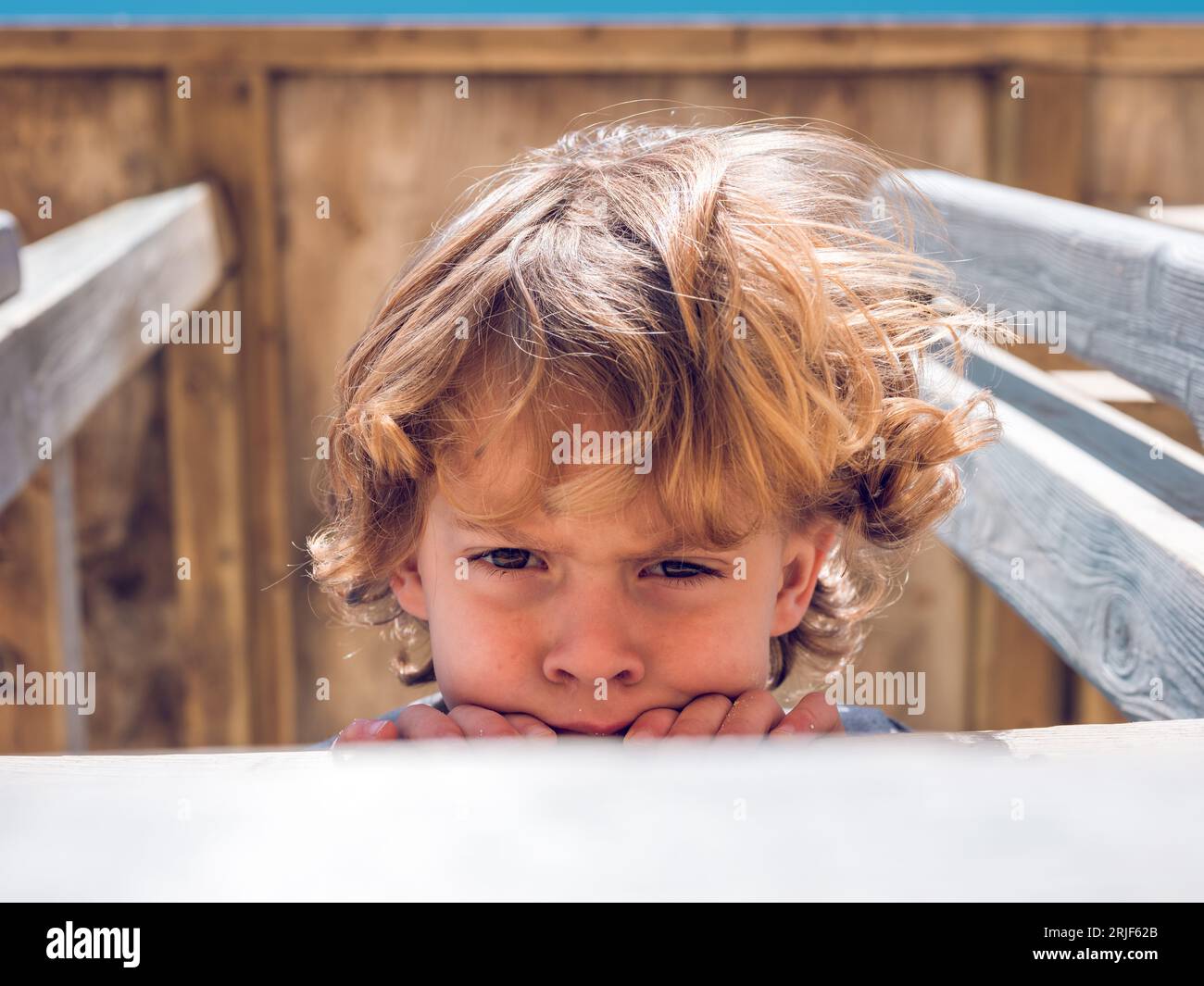 Low angle of offended blond boy looking at camera against blurred ...