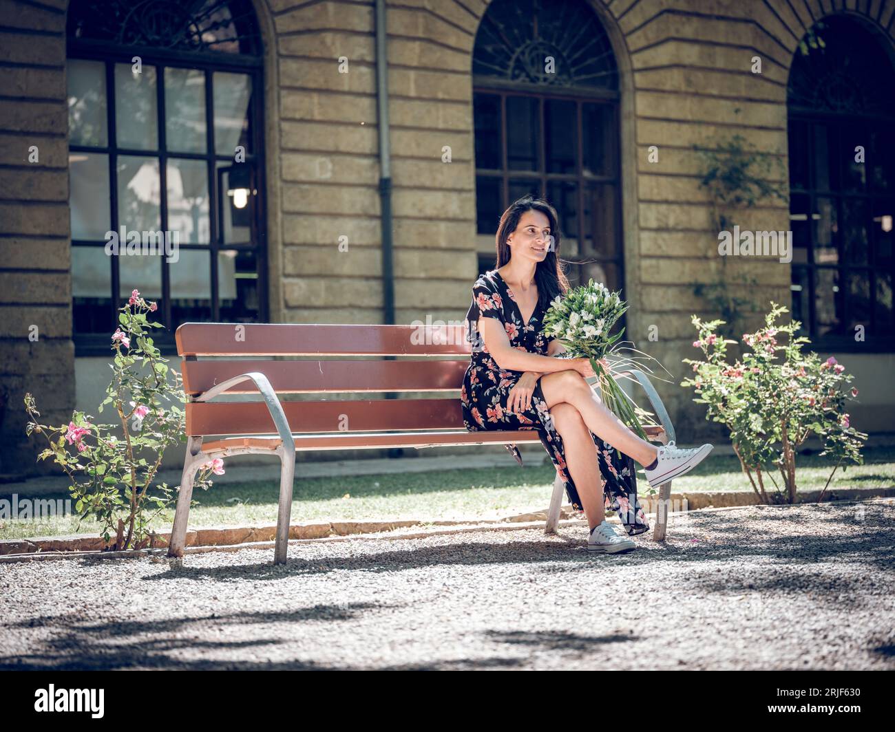 Side view of full body of attractive female resting on wooden bench ...