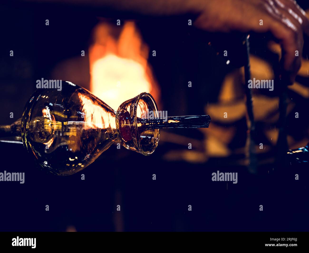 Pipe with shiny handmade glass bottle placed near burning flame of fire ...