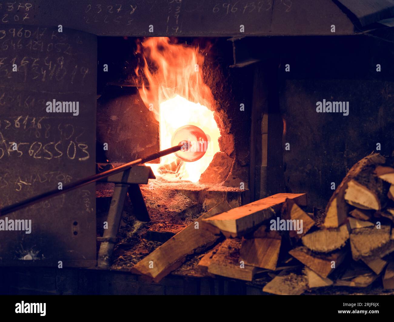 Pipe with glass vase placed in furnace with burning fire and firewood ...